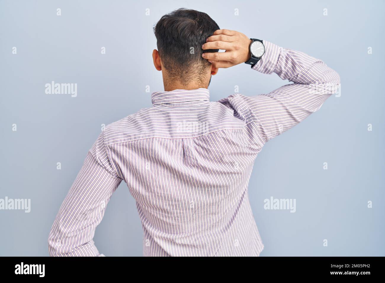 Arab man with beard standing over blue background backwards thinking ...