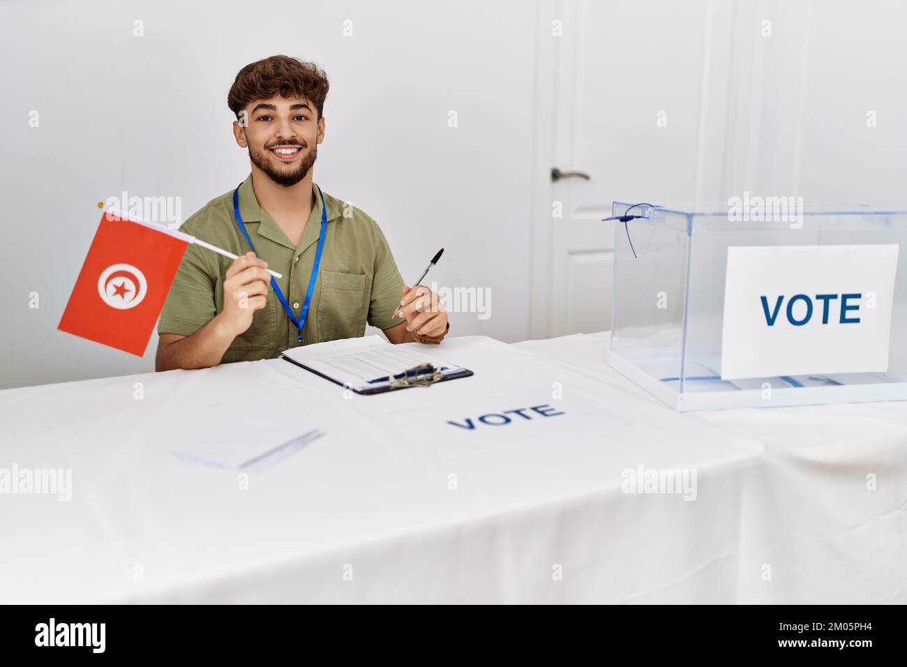 Young arab man smiling confident holding tunisia flag working at ...