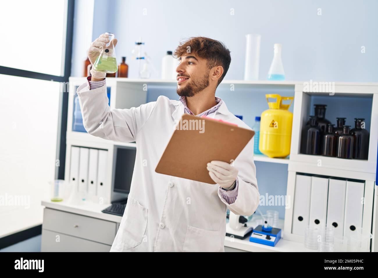Young arab man scientist measuring liquid reading report at laboratory Stock Photo - Alamy