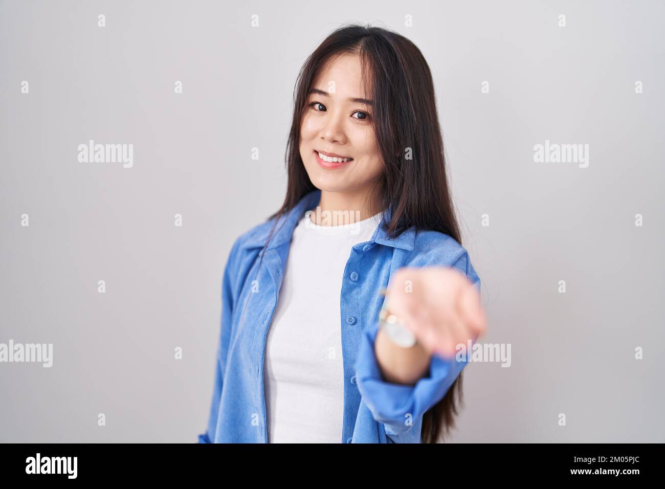 Young chinese woman standing over white background smiling cheerful ...