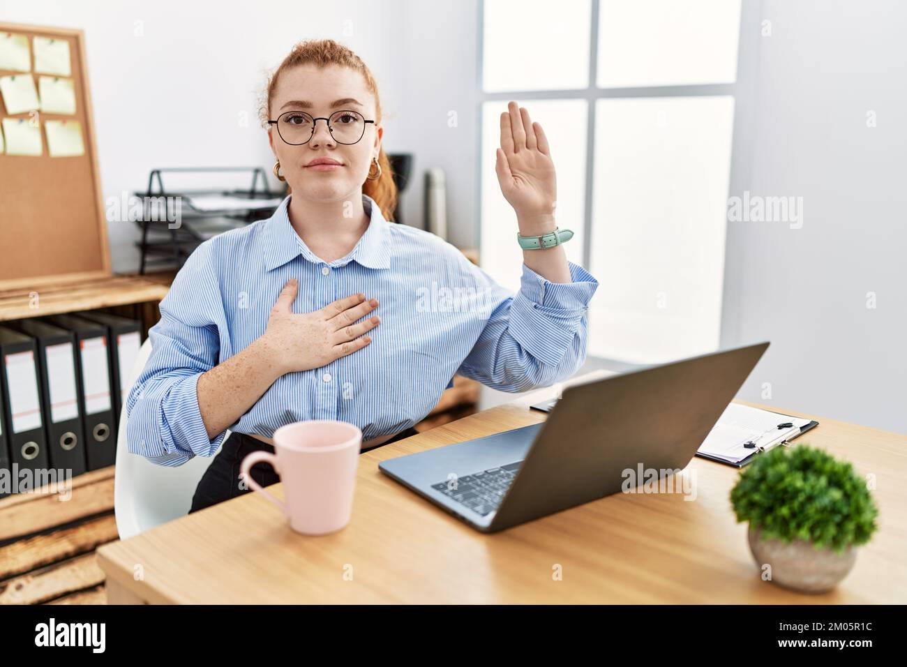 Young redhead woman working at the office using computer laptop ...