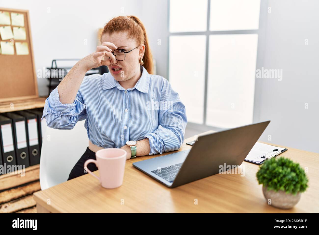 Young redhead woman working at the office using computer laptop ...