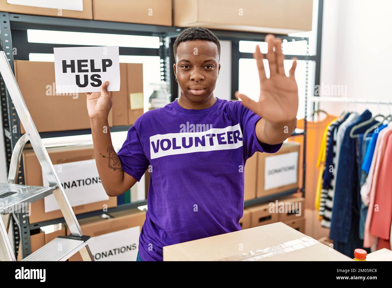 Young african volunteer man holding help us banner with open hand doing ...