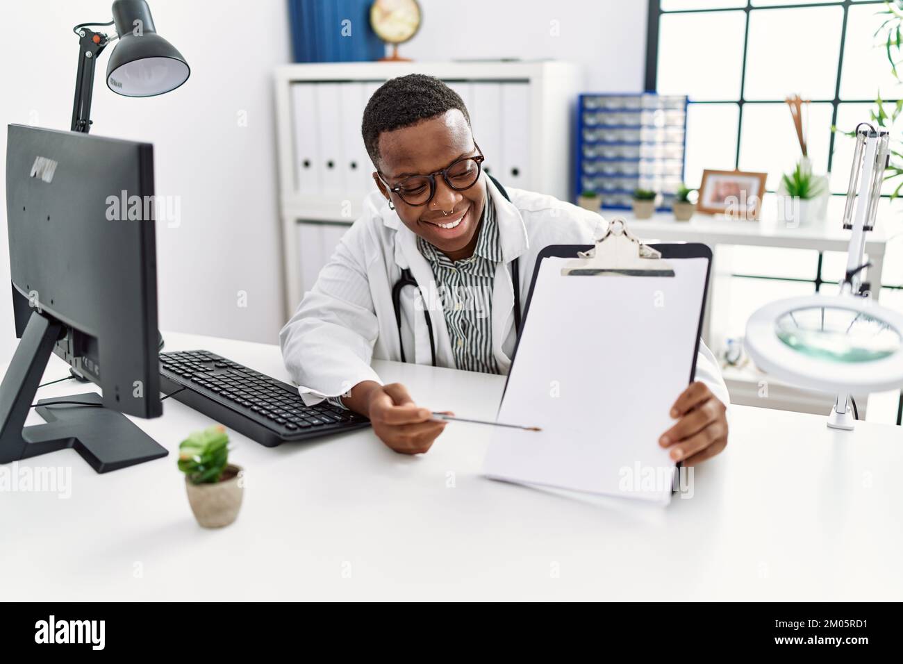 Young african man working as doctor showing clipboard at medical clinic ...