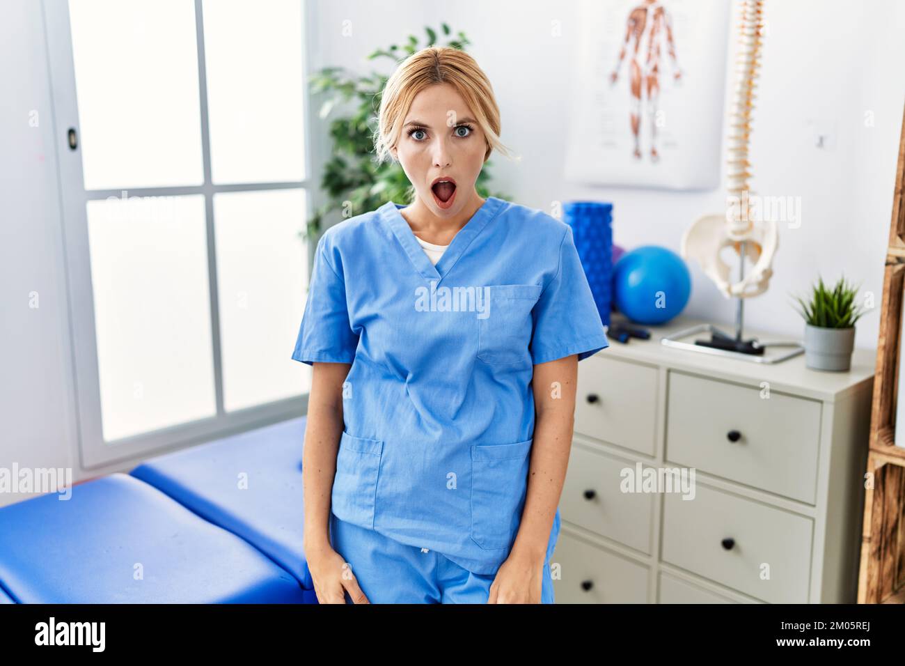 Beautiful blonde physiotherapist woman working at pain recovery clinic ...