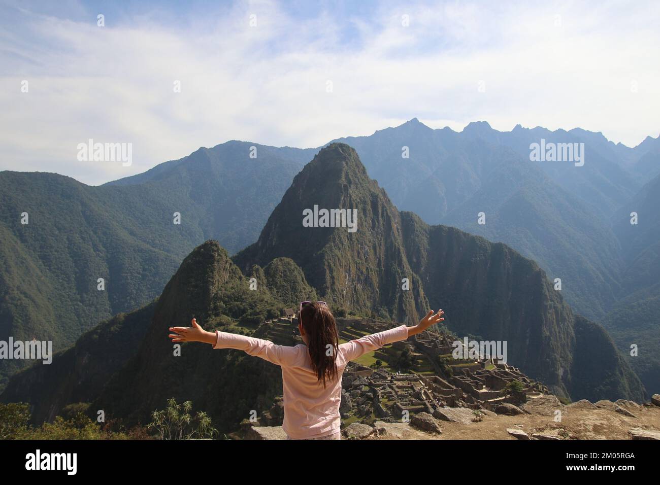 Person standing in front of Machu Pichu with arms open Stock Photo - Alamy