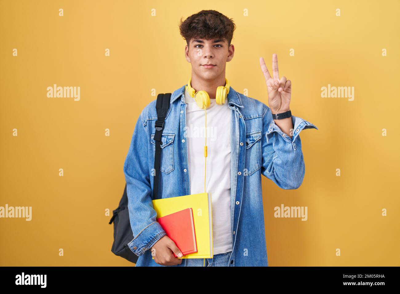 Hispanic teenager wearing student backpack and holding books smiling ...