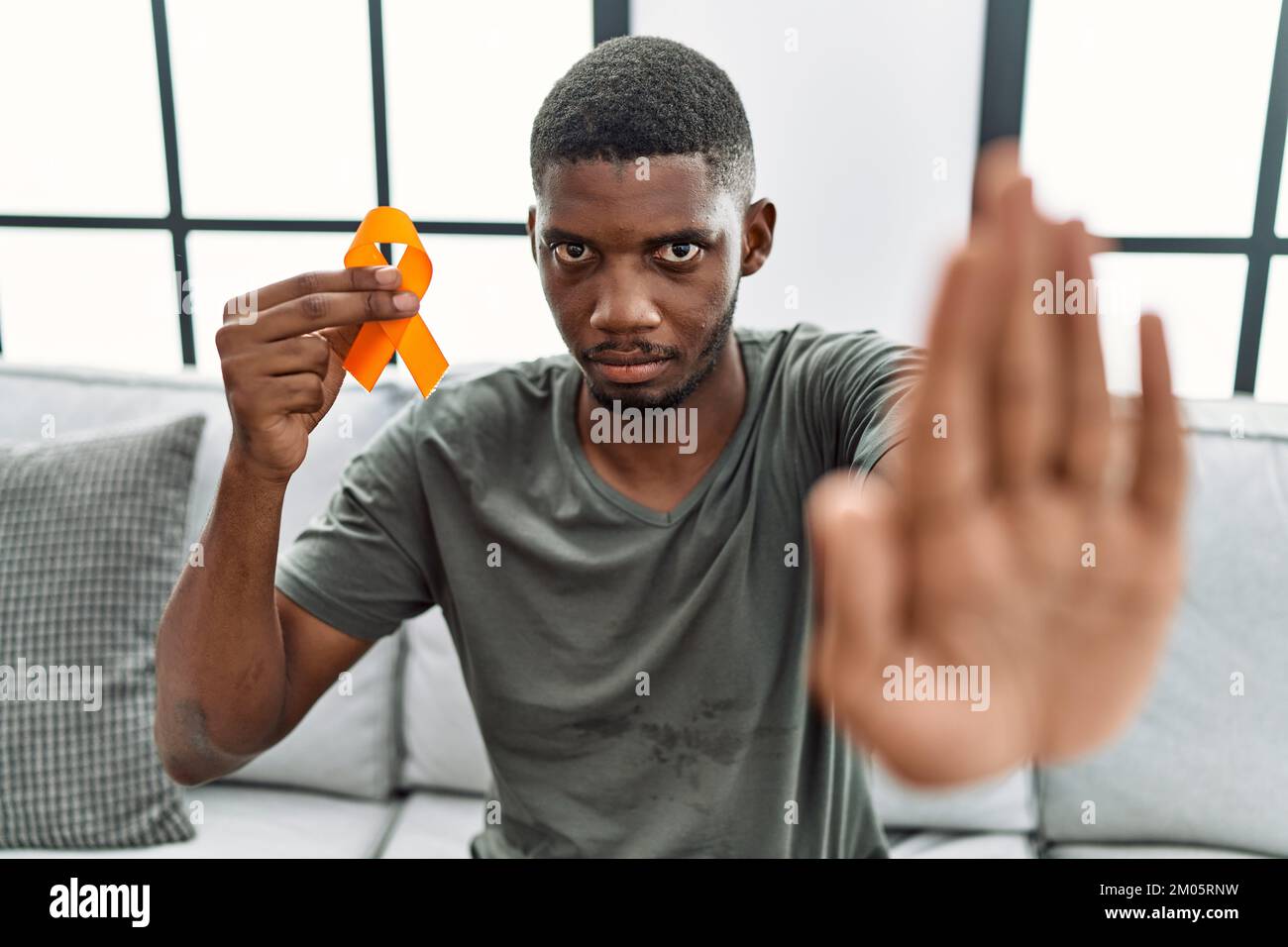 Young african american man holding awareness orange ribbon sitting on ...
