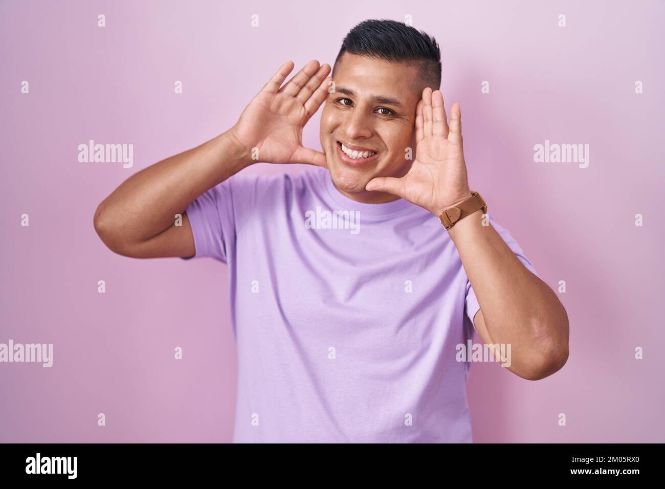 Young hispanic man standing over pink background smiling cheerful ...
