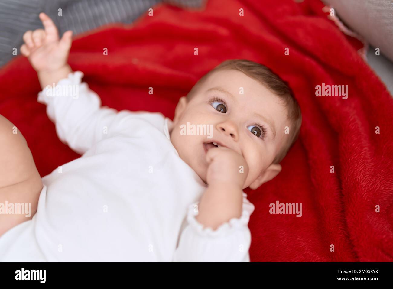 Adorable toddler lying on sofa bitting fingers at home Stock Photo - Alamy