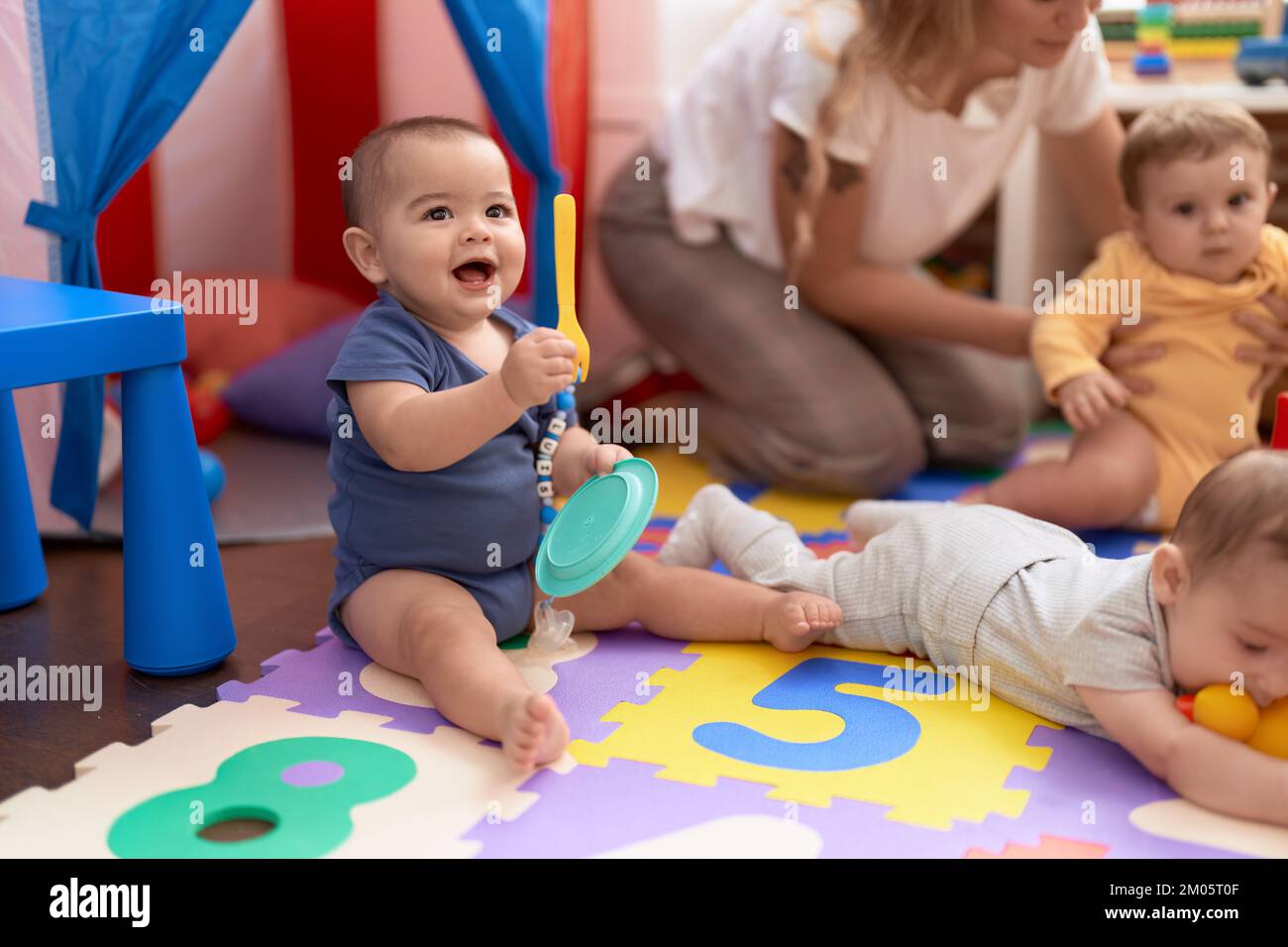Group of toddlers playing with dish toy sitting on floor at ...