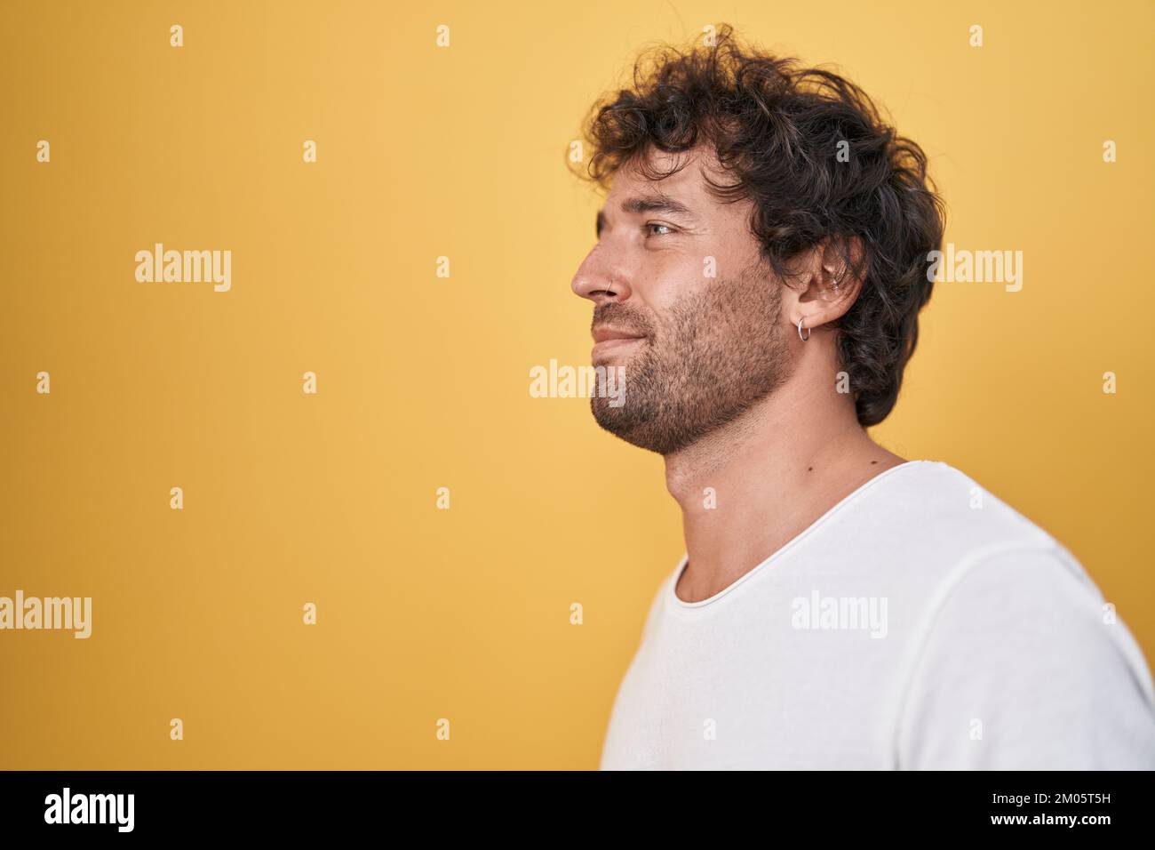 Young hispanic man standing looking to the side over isolated yellow ...