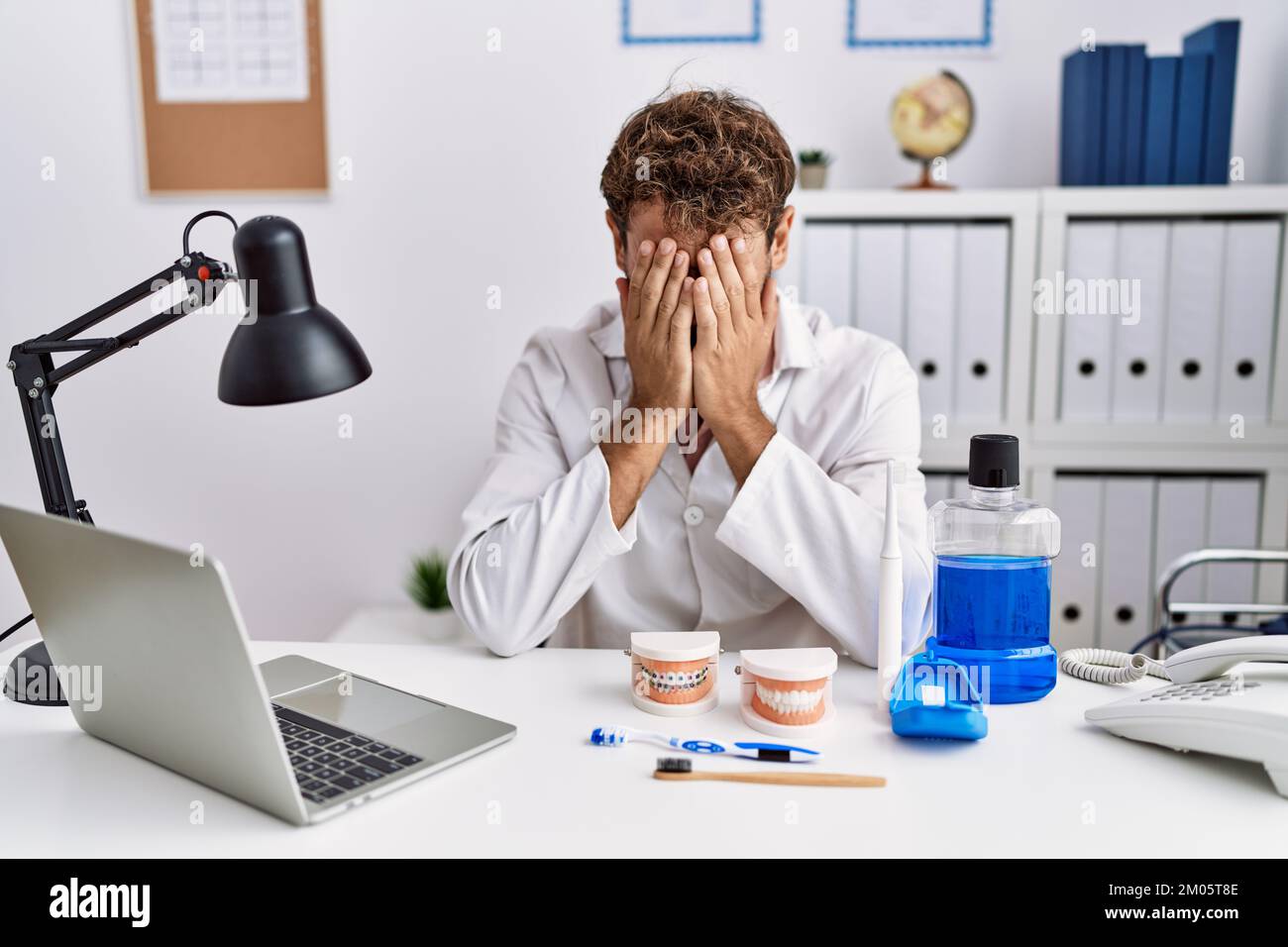 Young hispanic dentist man working at medical clinic with sad ...