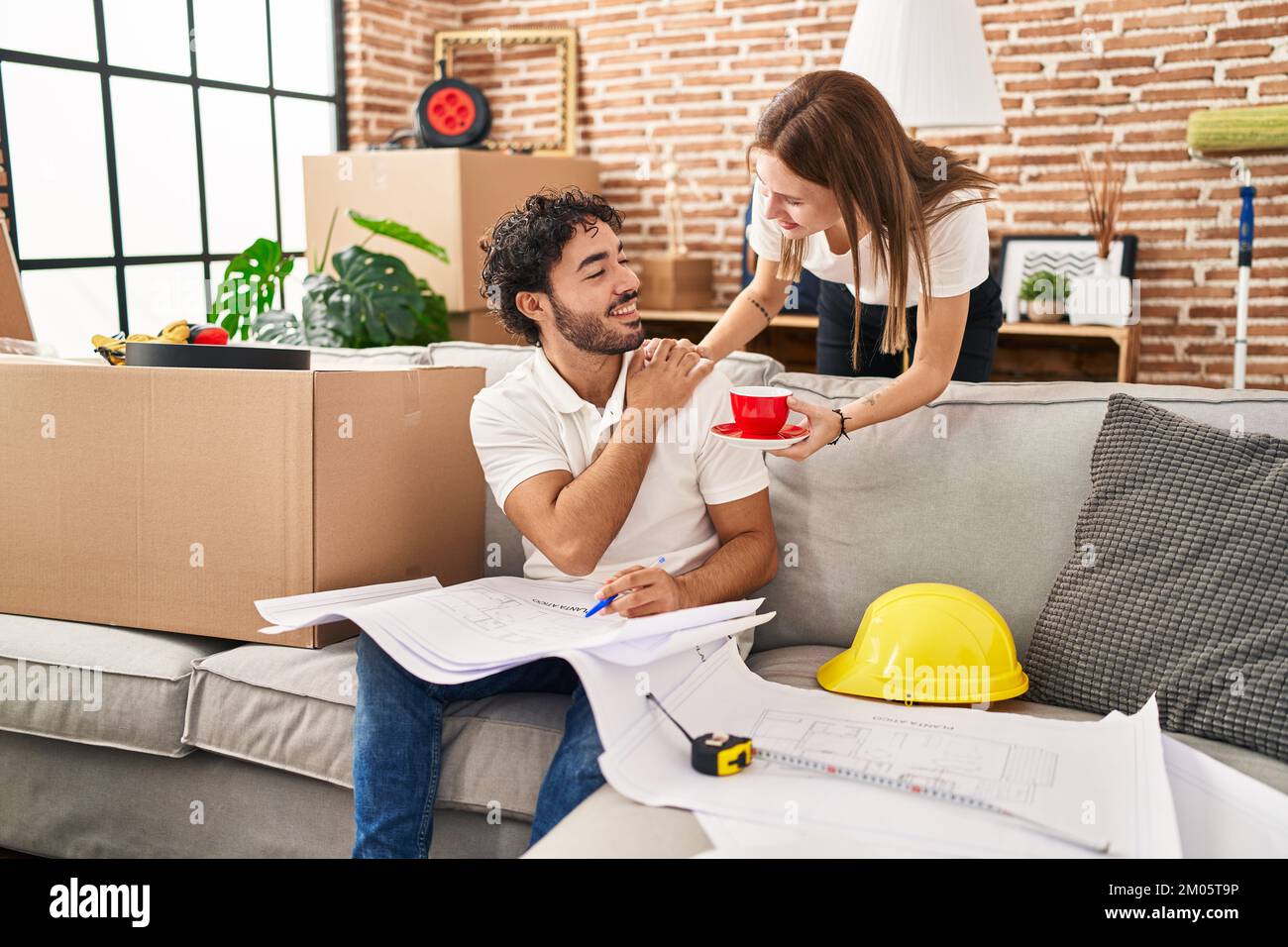 Man and woman couple drinking coffee looking house plans at new home ...