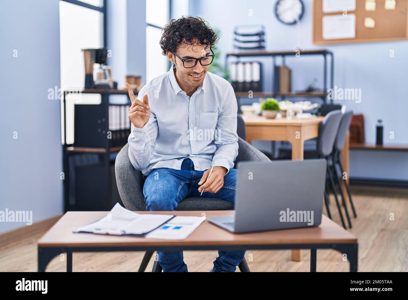 Hispanic man doing video call waving to laptop smiling happy pointing ...