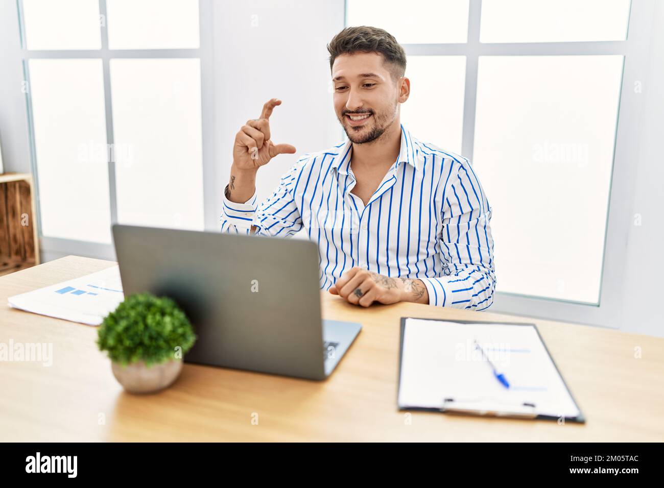 Young handsome man with beard working at the office using computer ...