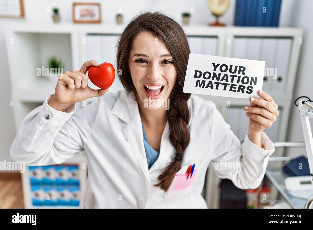 Young doctor woman holding your donation matters banner at the clinic ...