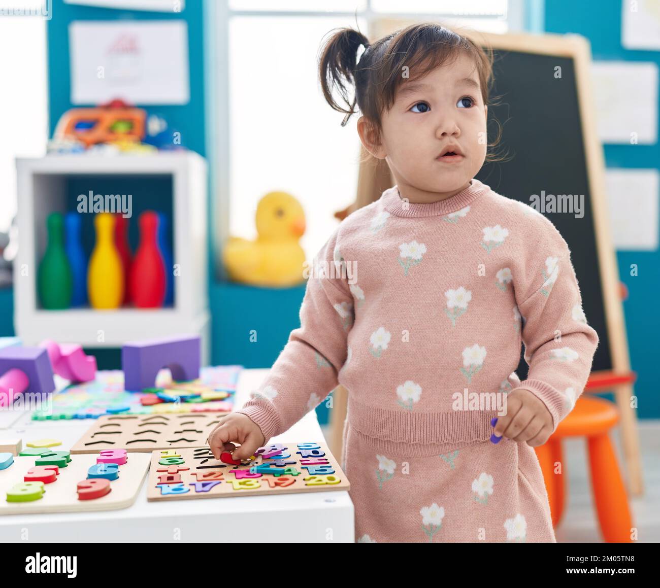 Adorable chinese girl playing with maths puzzle game standing at ...
