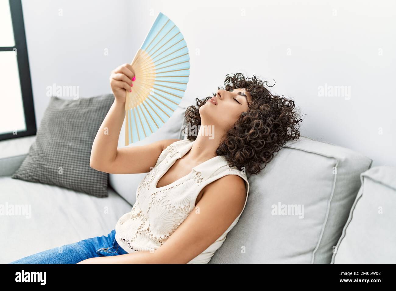 Young middle east woman desperate using hand fan at home Stock Photo ...
