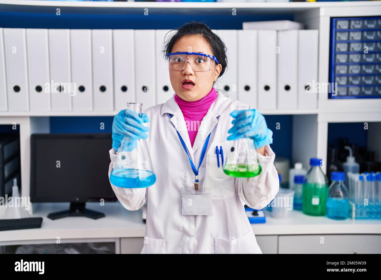 Young asian woman working at scientist laboratory in shock face ...