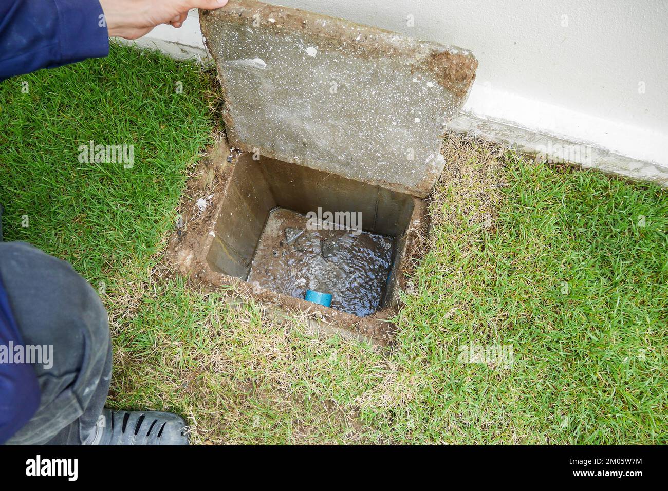 Worker hand open sewer cover of new house Stock Photo - Alamy