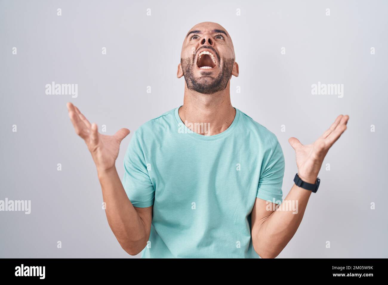Middle age bald man standing over white background crazy and mad ...