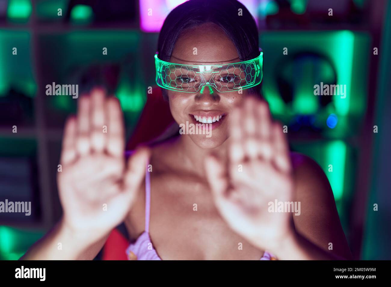 Young hispanic woman streamer using virtual reality glasses at gaming ...