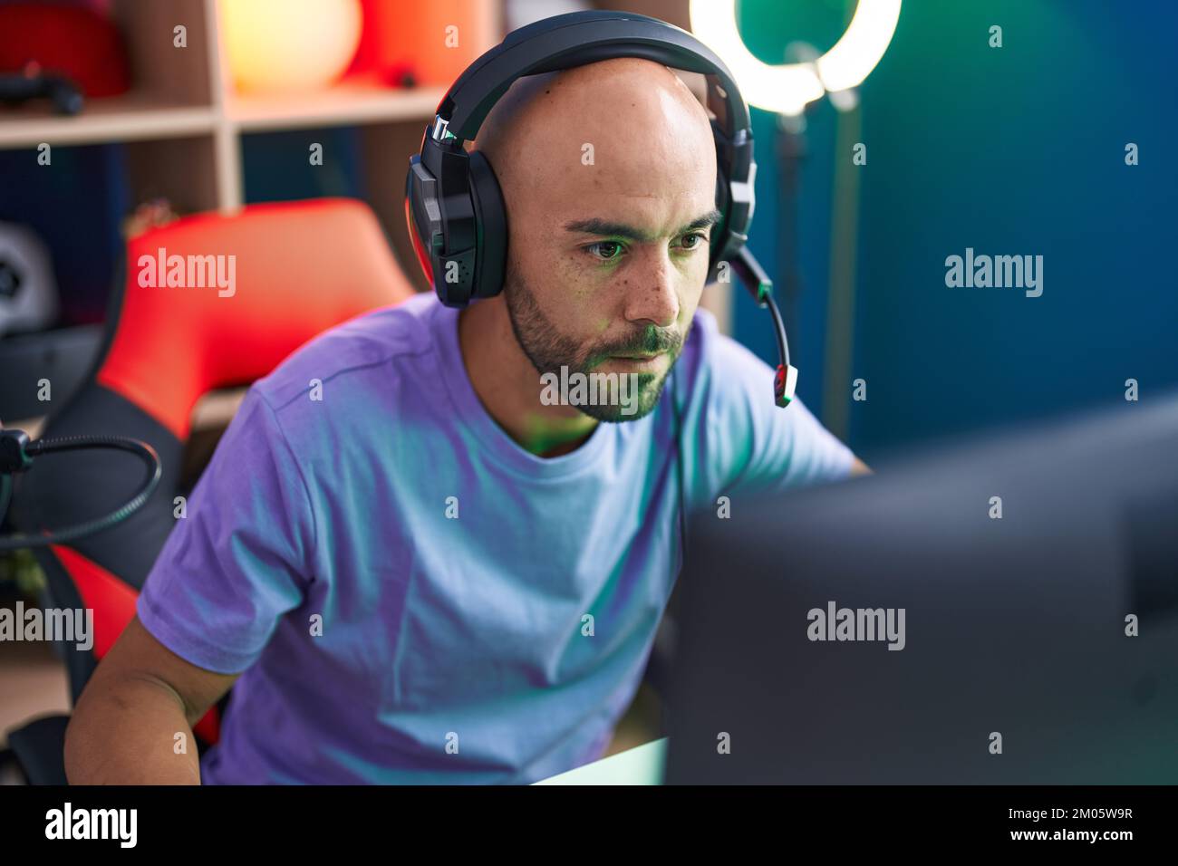 Young bald man streamer playing video game using computer at gaming ...