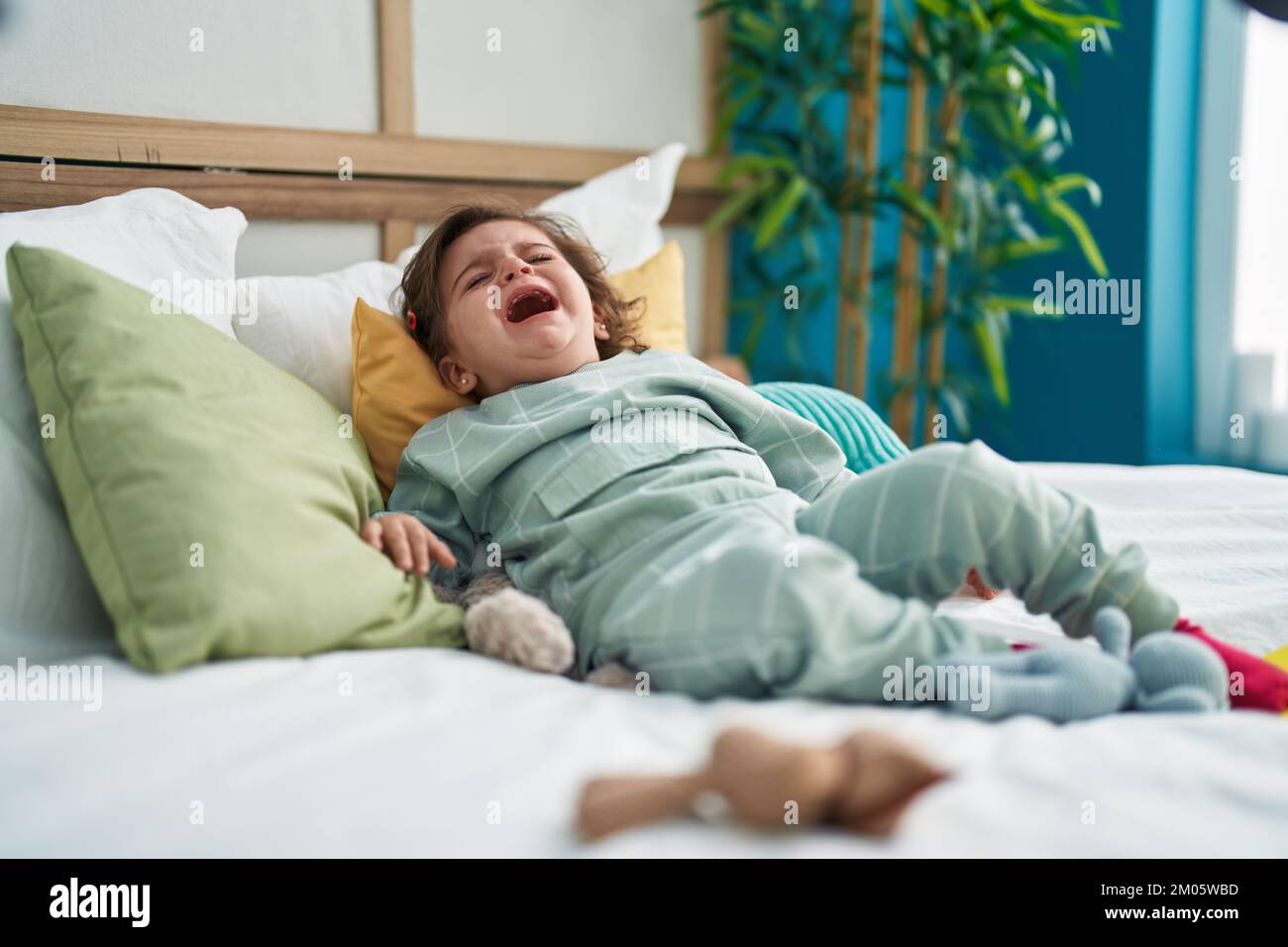 Adorable hispanic girl lying on bed crying at bedroom Stock Photo - Alamy