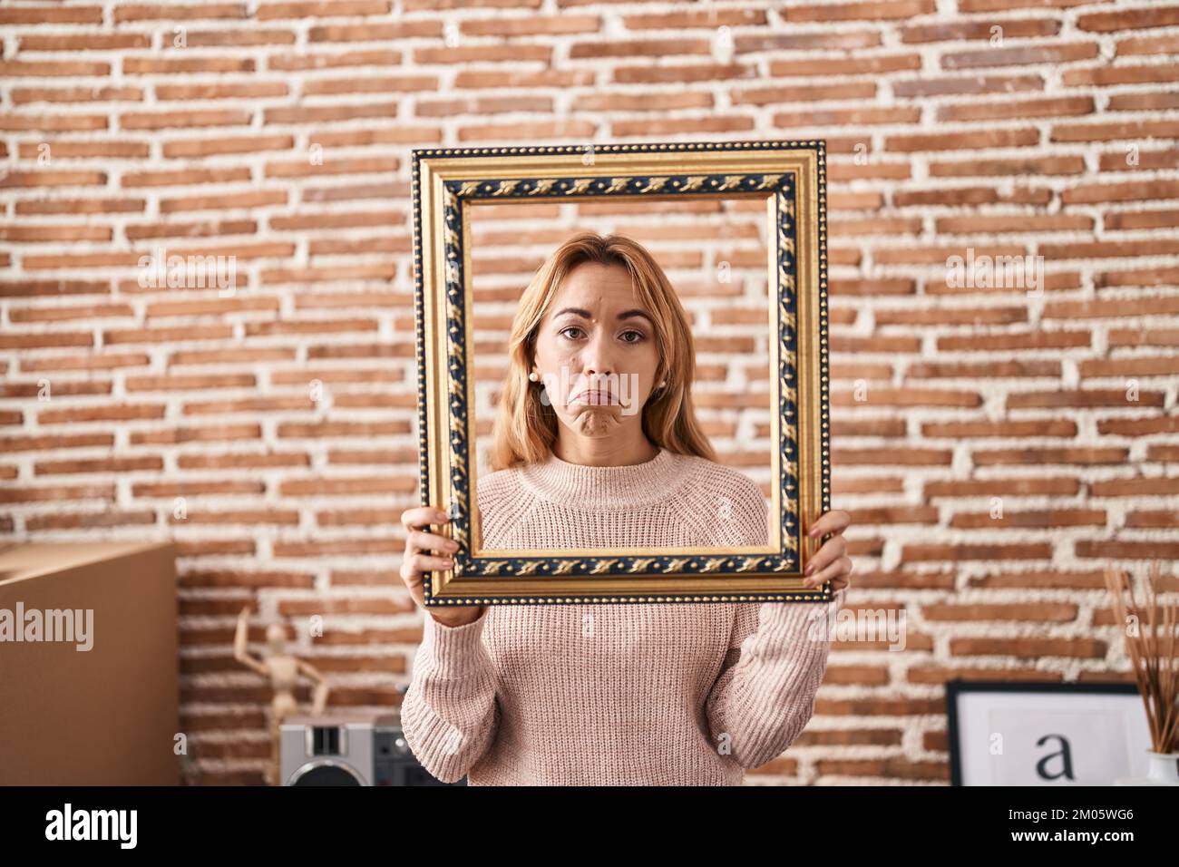 Hispanic woman holding empty frame depressed and worry for distress ...