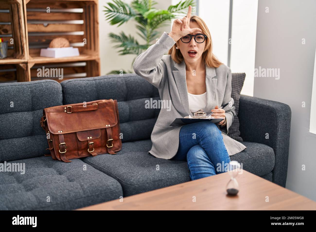 Hispanic woman working at consultation office making fun of people with ...