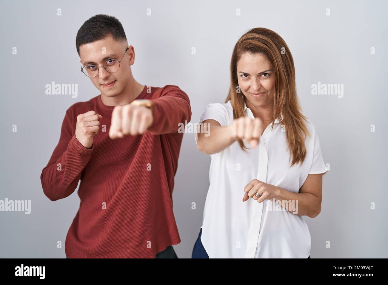 Mother and son standing together over isolated background punching fist ...