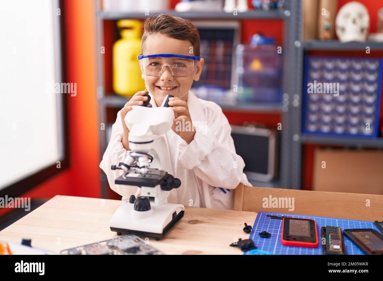 Adorable hispanic toddler student using microscope standing at ...