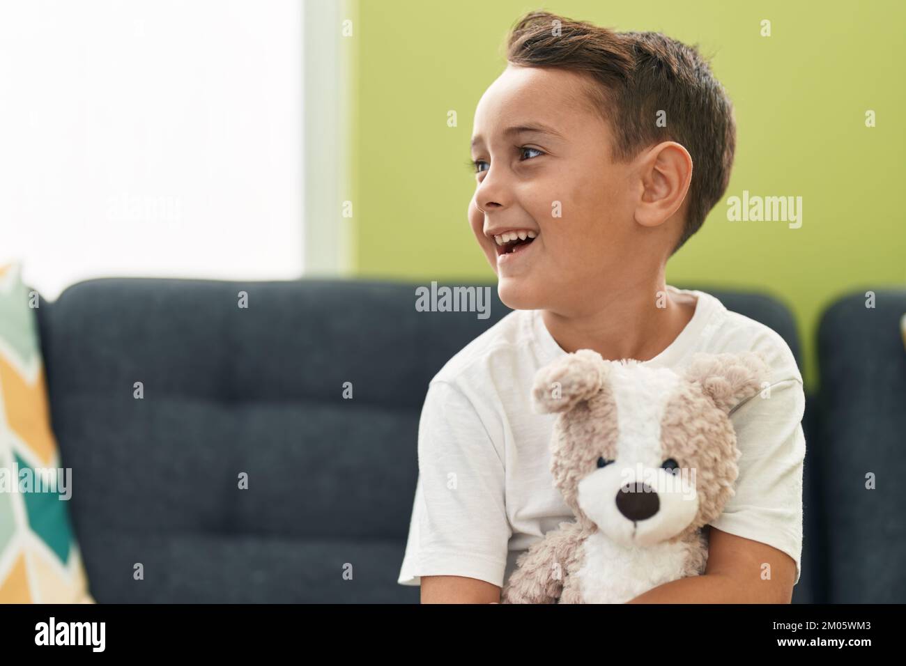 Adorable hispanic toddler hugging teddy bear sitting on sofa at home ...