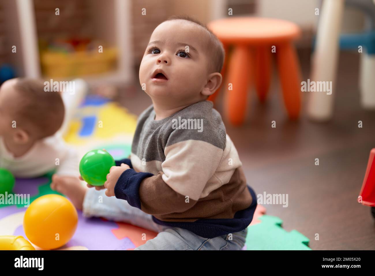 Adorable chinese toddler playing with ball sitting on floor at ...