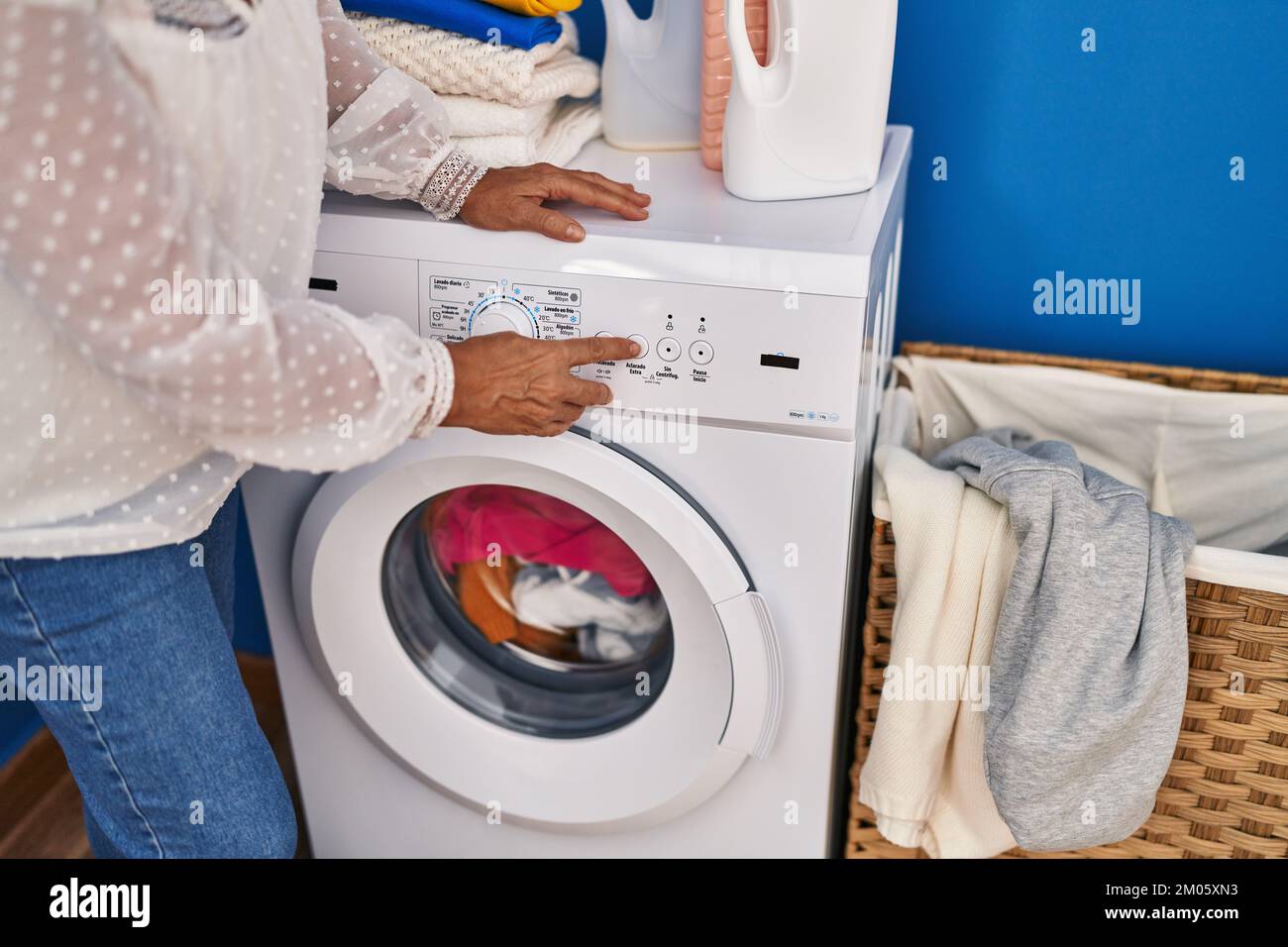 Middle age woman turning on washing machine at laundry room Stock Photo ...