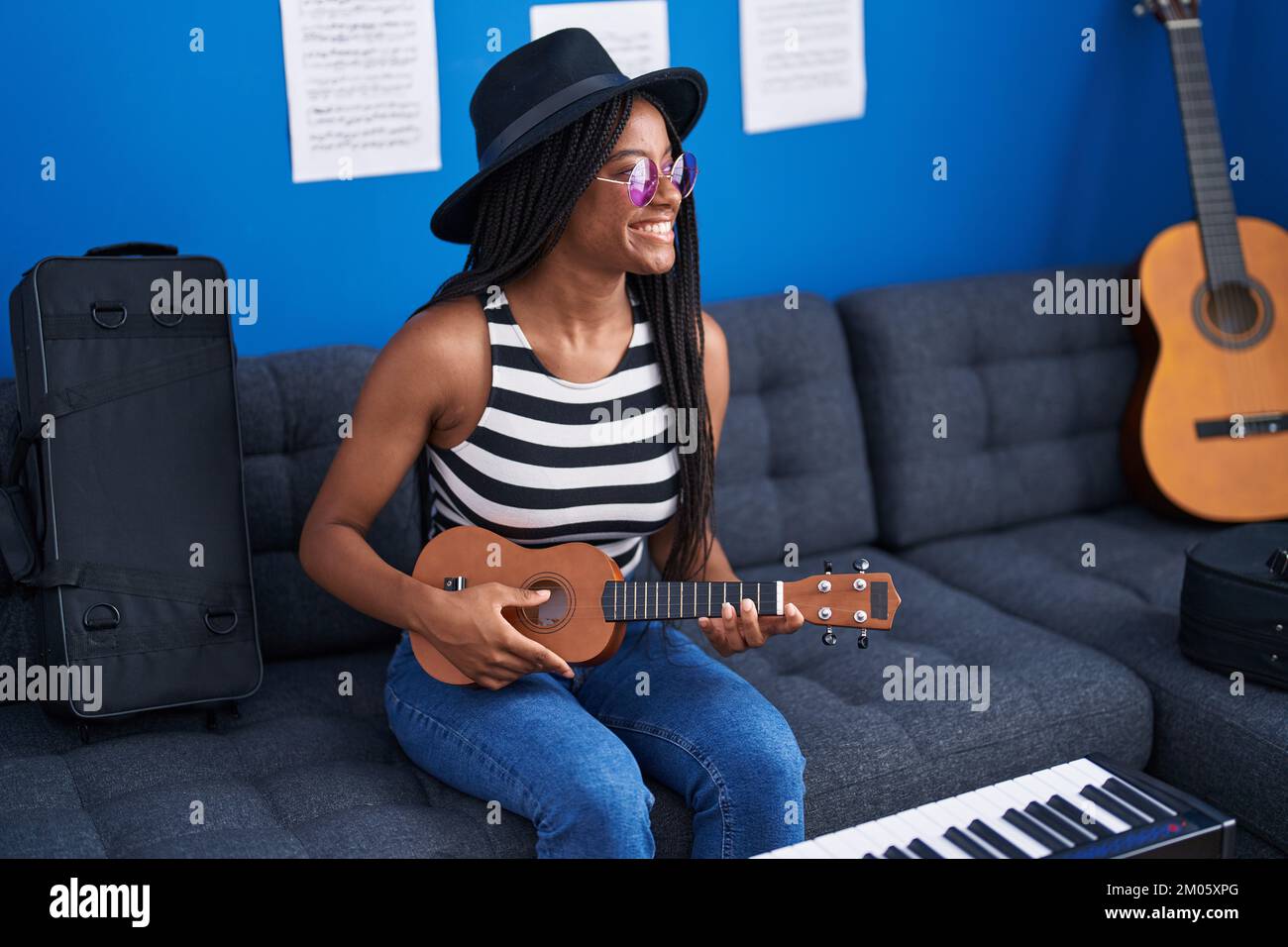 African american woman musician playing ukulele at music studio Stock ...