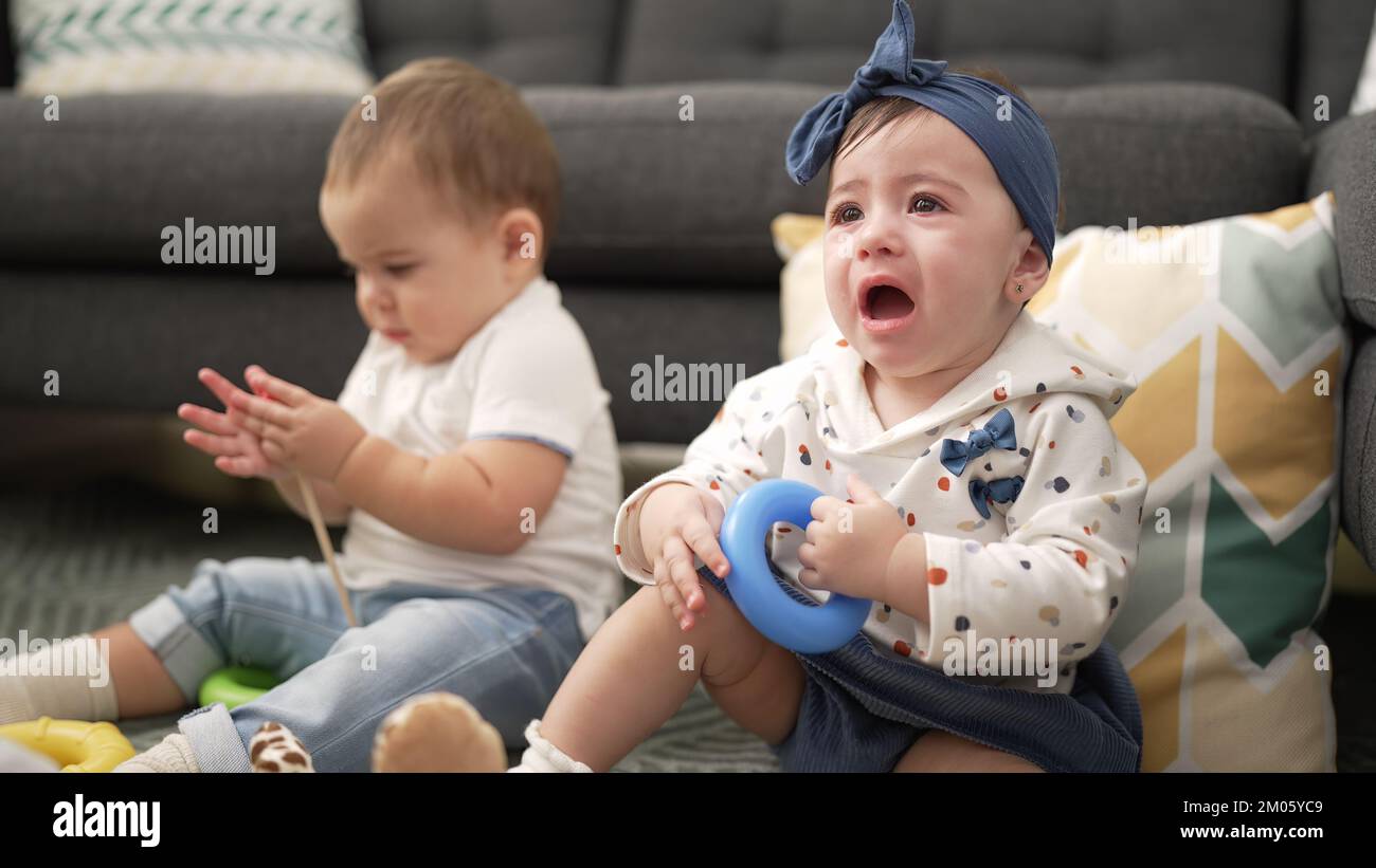 Two toddlers playing with toys crying at home Stock Photo - Alamy