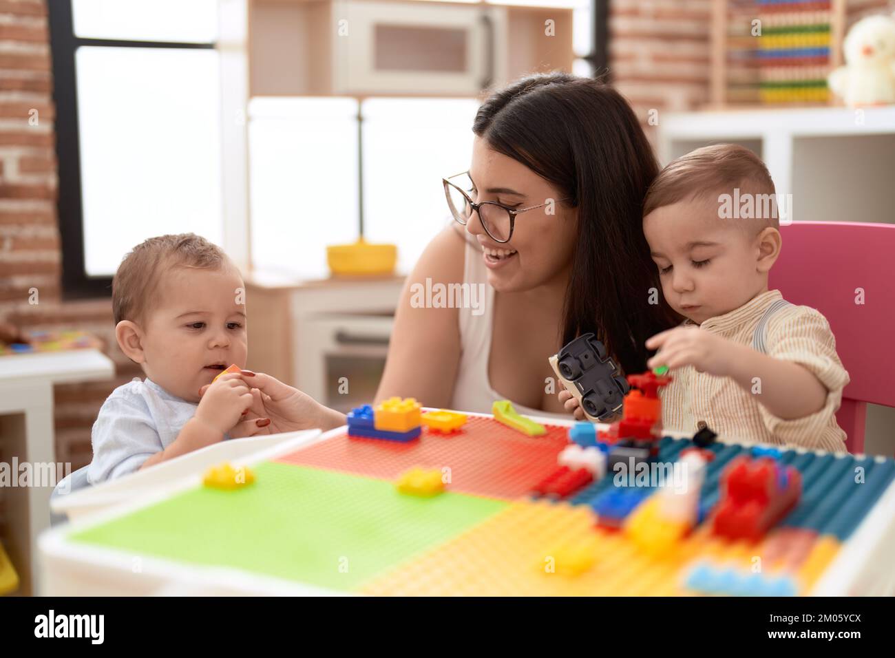 Teacher and preschool students playing with construction blocks sitting ...