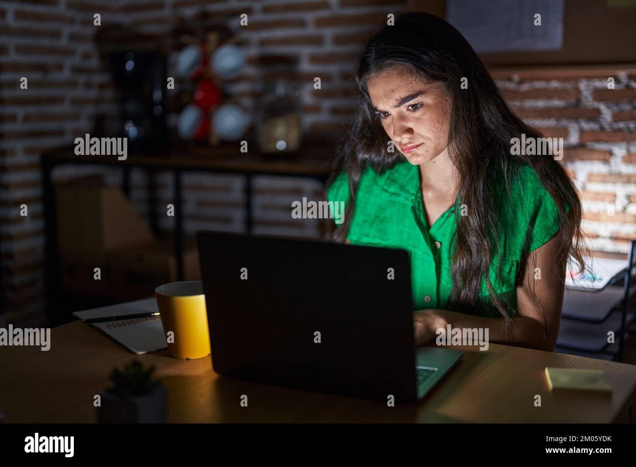 Young teenager girl working at the office at night depressed and worry ...
