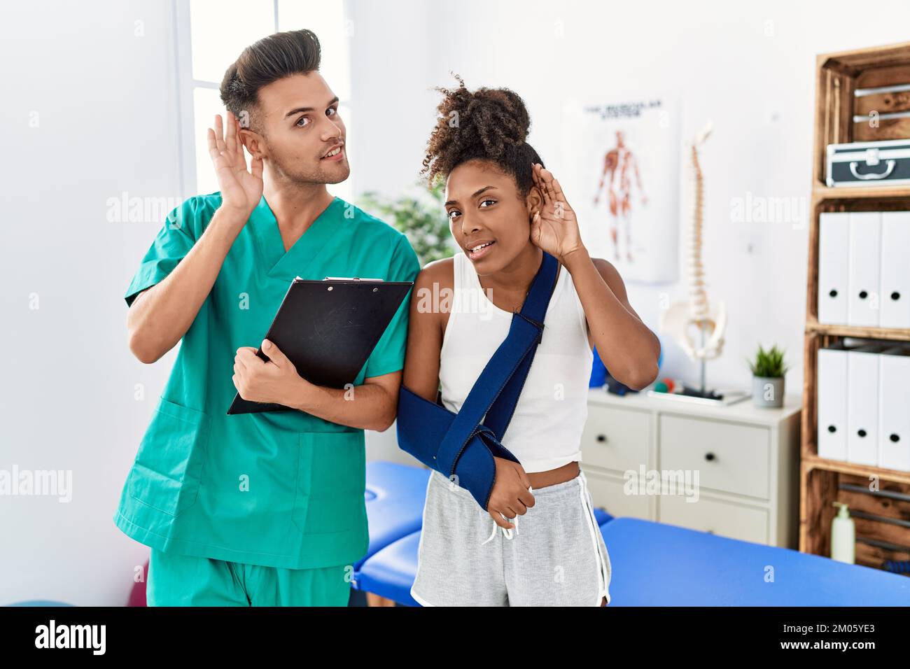 Physiotherapist working with patient wearing arm on sling at ...
