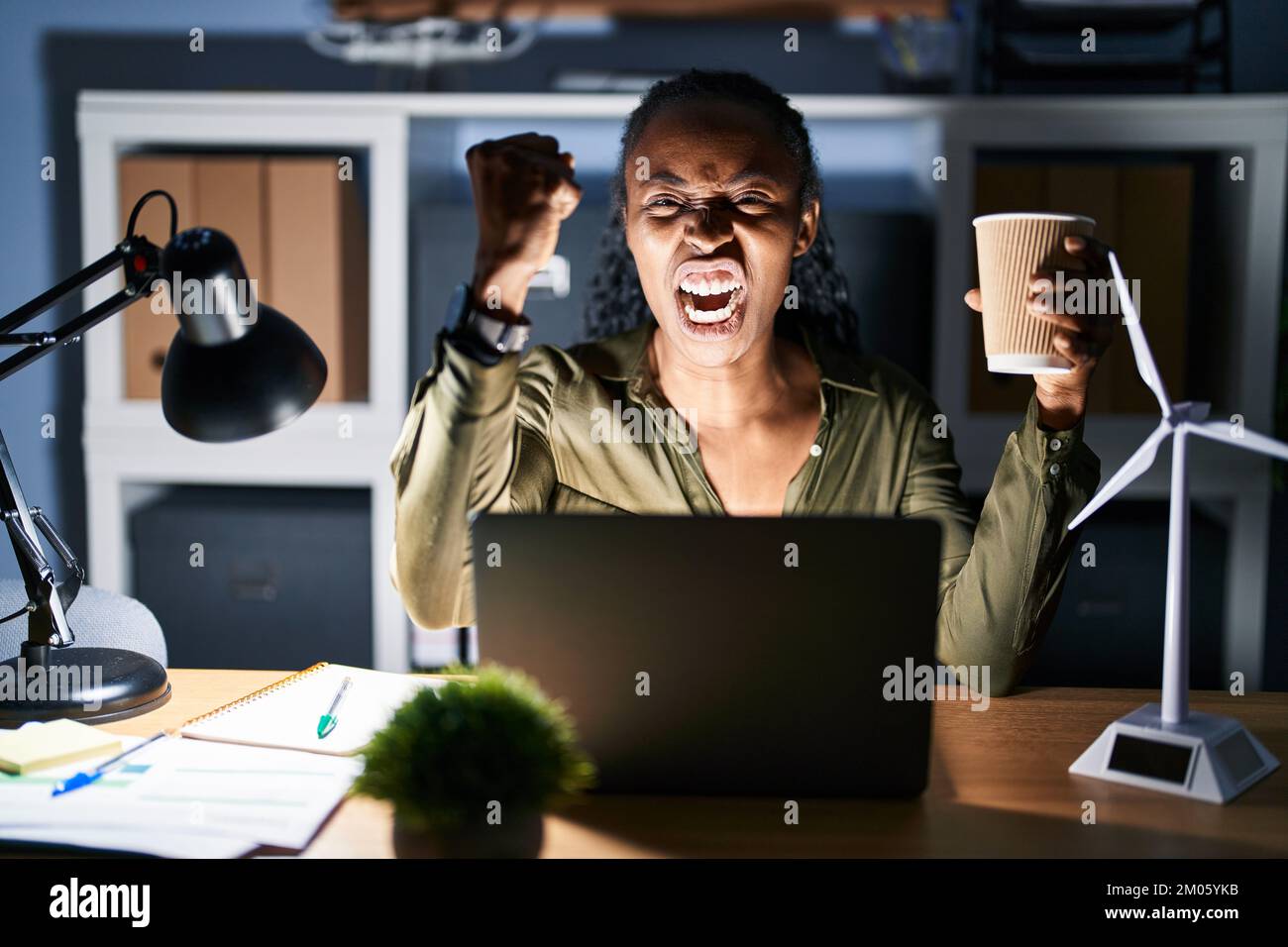 African woman working using computer laptop at night angry and mad ...