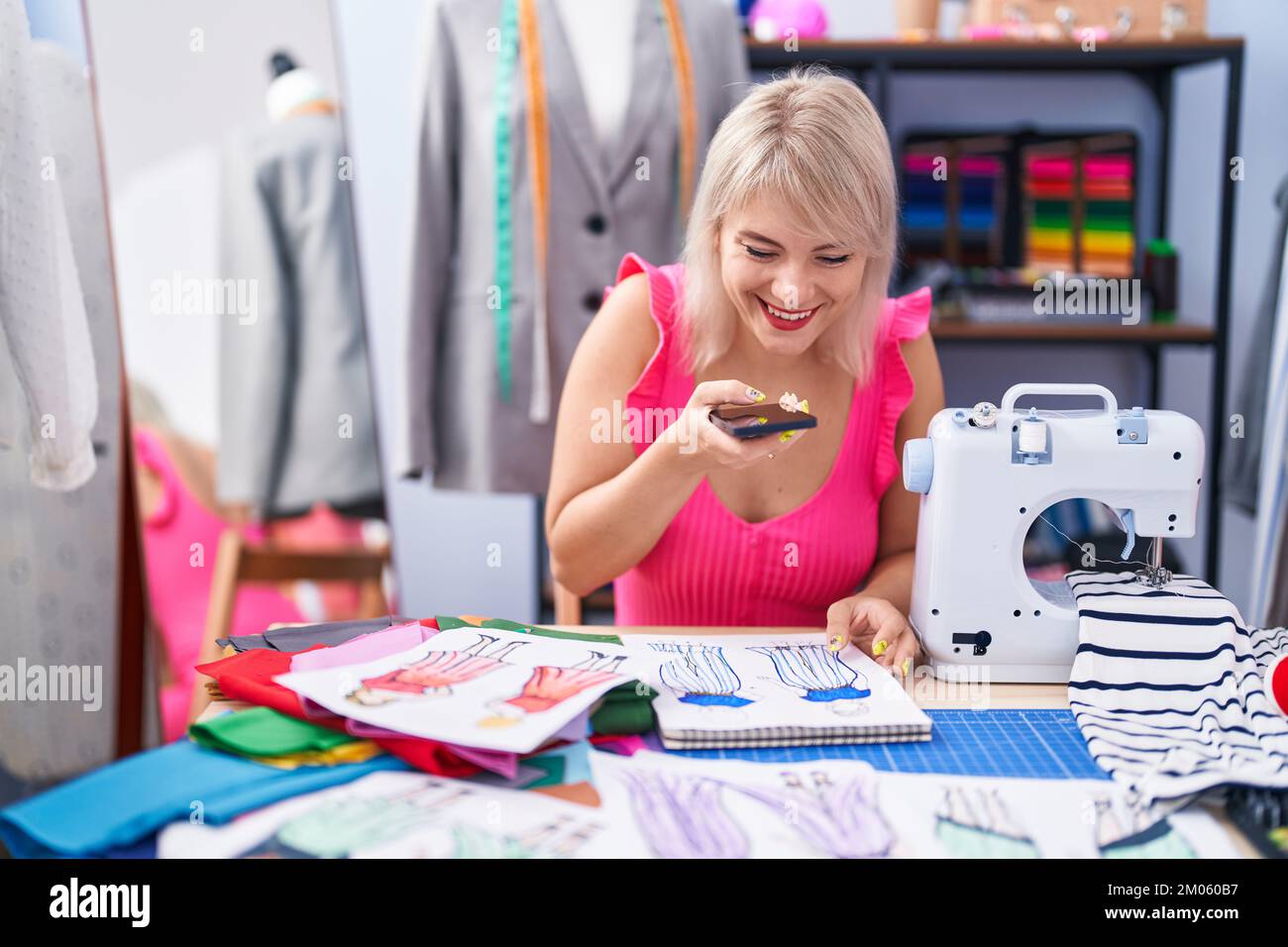 Young blonde woman tailor make photo by smartphone to clothing design ...