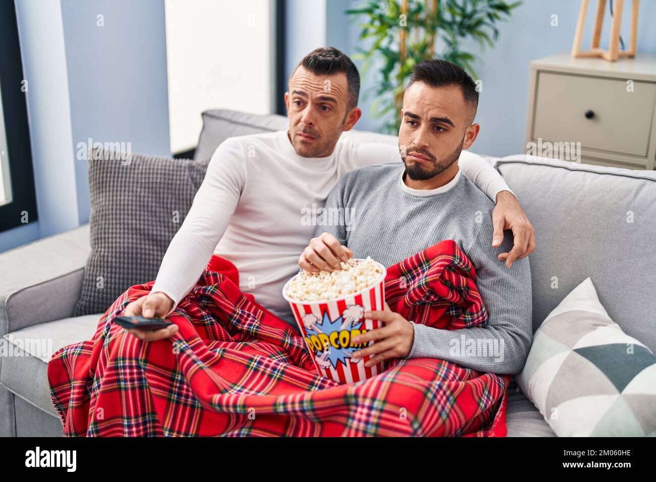 Homosexual couple eating popcorn watching tv depressed and worry for ...