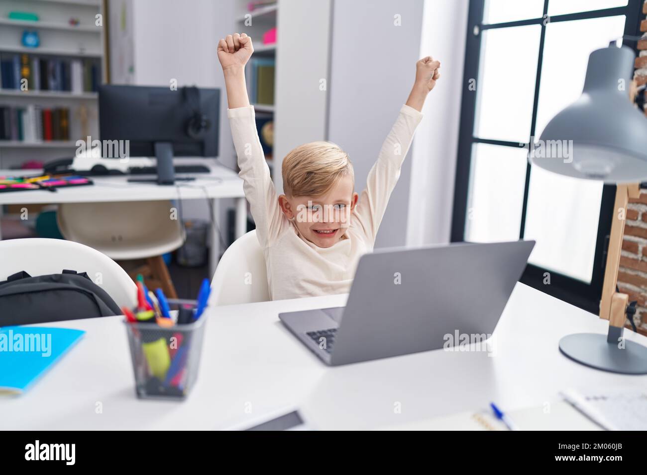 Adorable toddler student using laptop with winner expression at ...