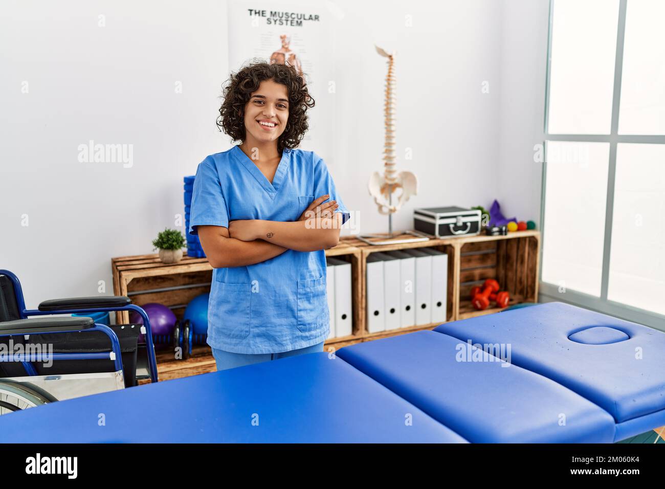 Young hispanic woman wearing physio therapist uniform standing with ...