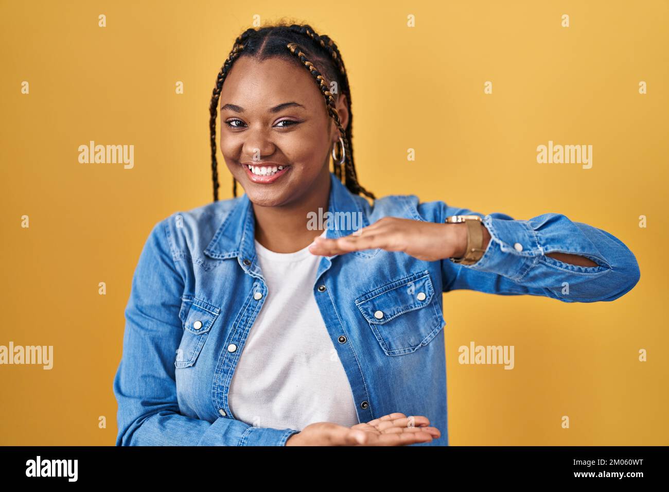 African american woman with braids standing over yellow background ...