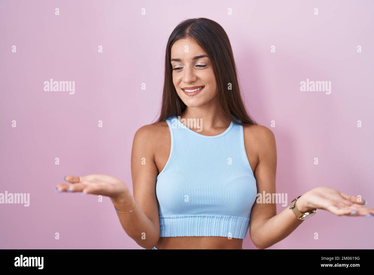 Young brunette woman standing over pink background smiling showing both ...