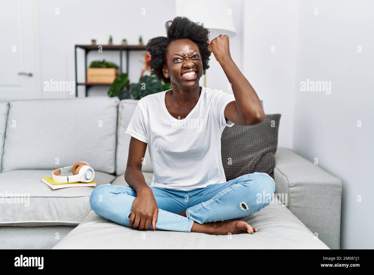 African young woman sitting on the sofa at home angry and mad raising ...