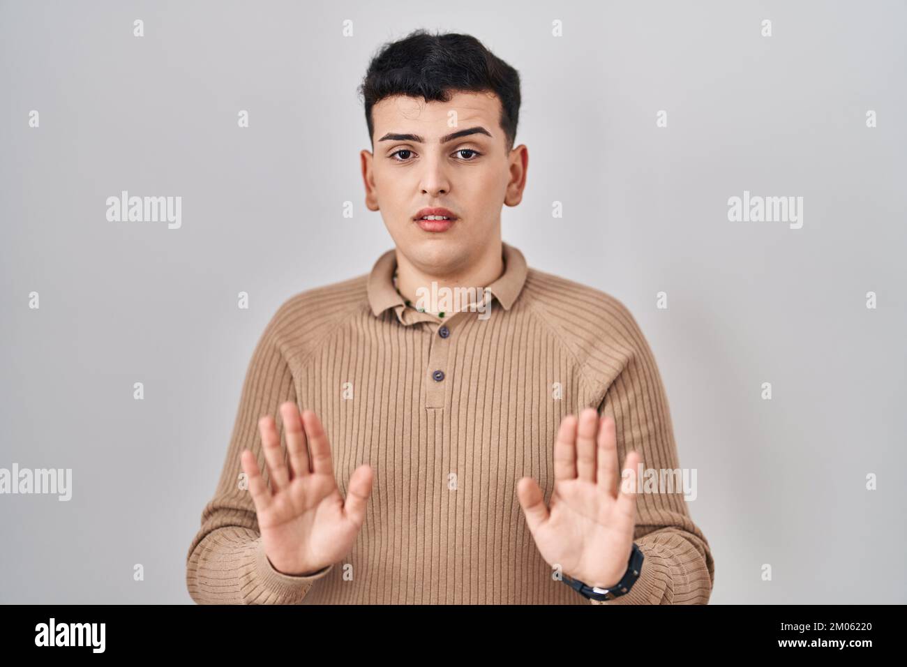 Non binary person standing over isolated background moving away hands ...